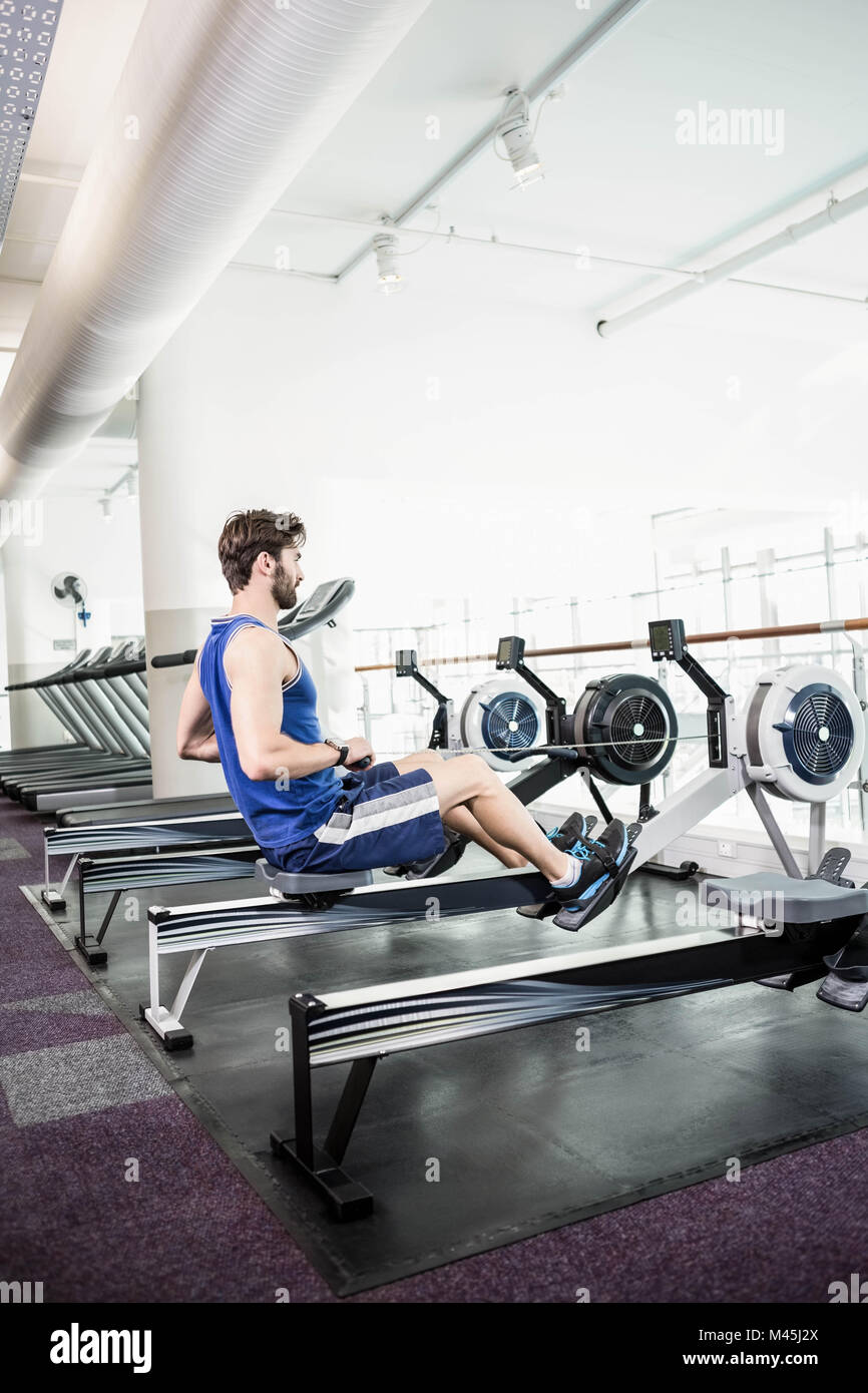 Handsome man doing exercise on drawing machine Stock Photo - Alamy