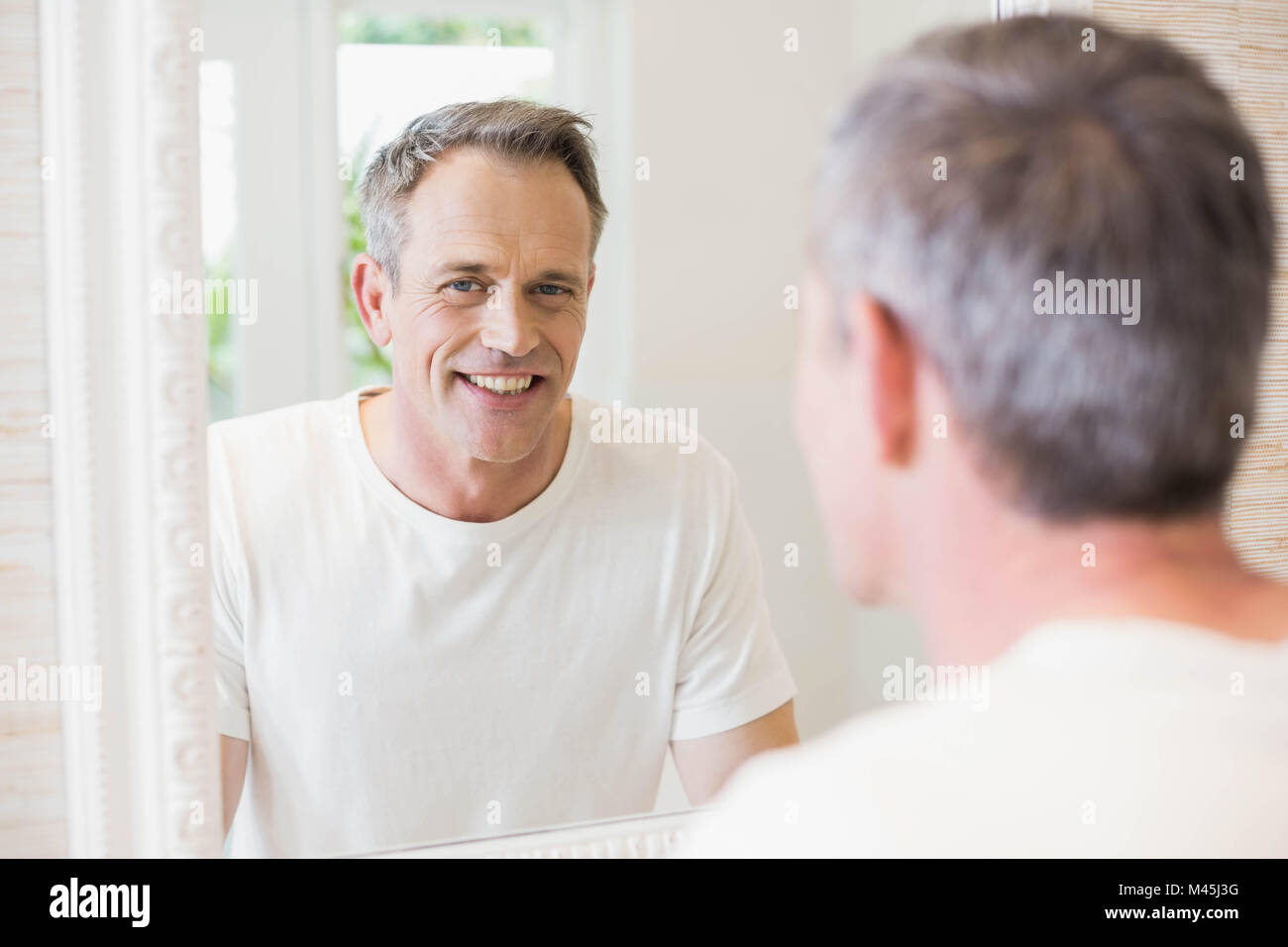 Handsome man looking at himself in the mirror Stock Photo - Alamy