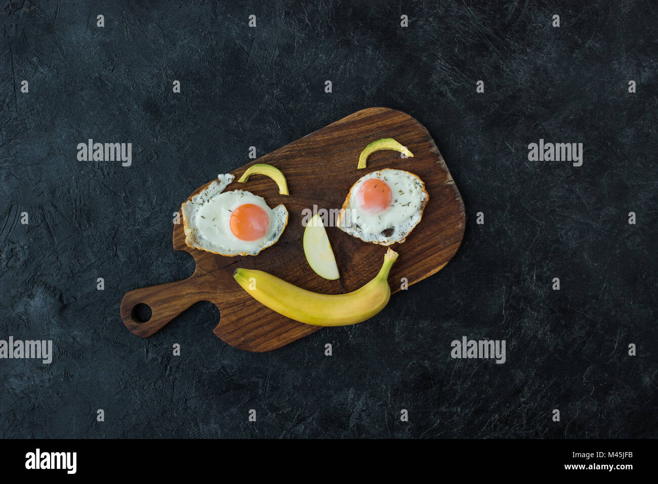 top view of smiling face made of food for healthy breakfast on cutting ...