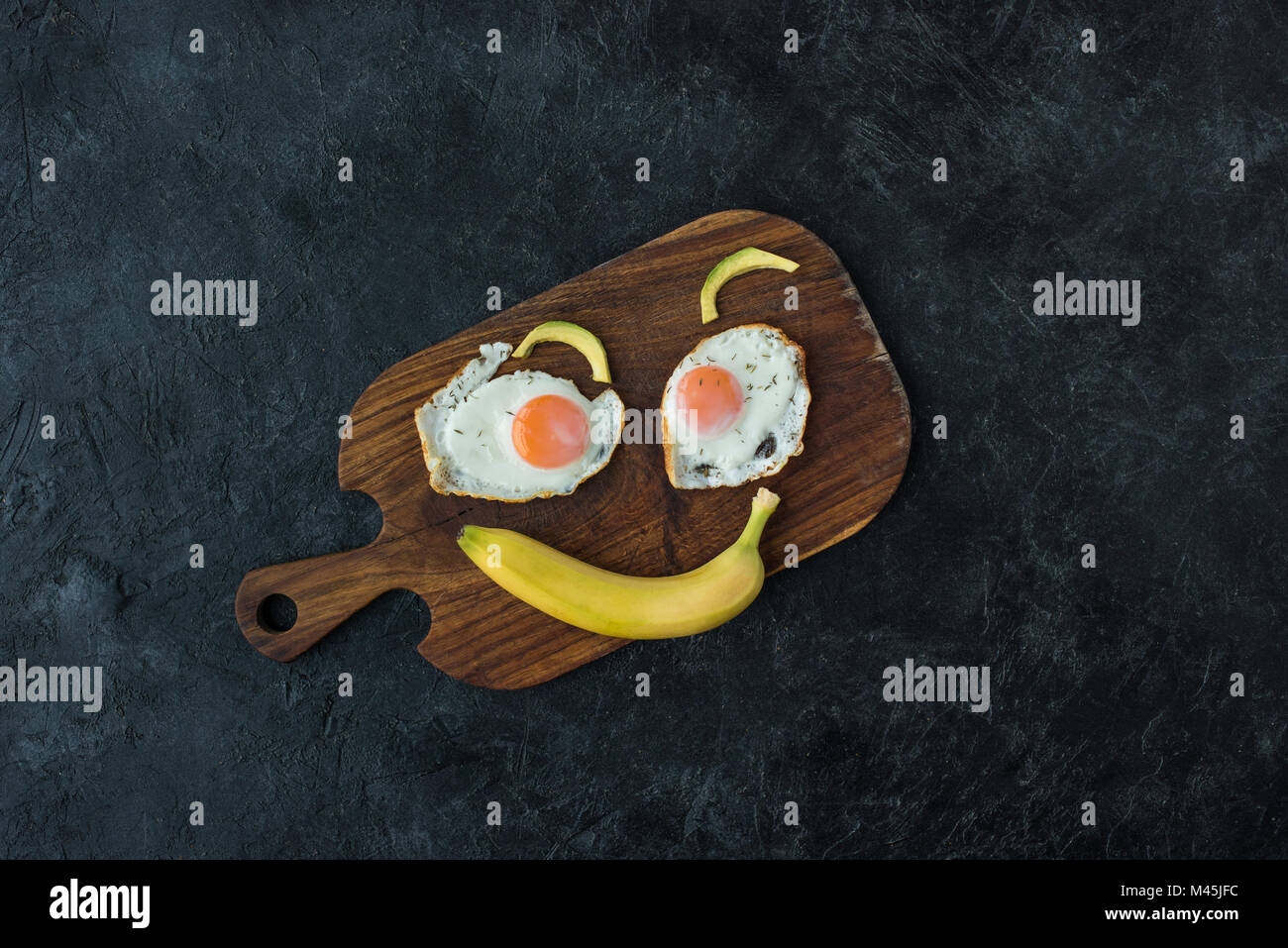 top view of smiling face made of food for healthy breakfast on cutting ...