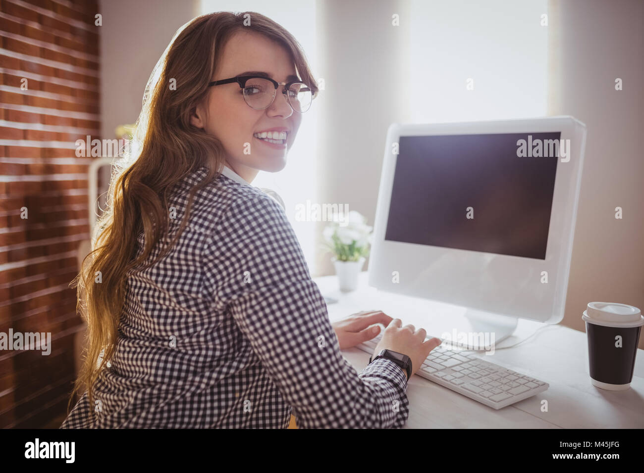 Smiling hipster businesswoman typing on computer Stock Photo - Alamy