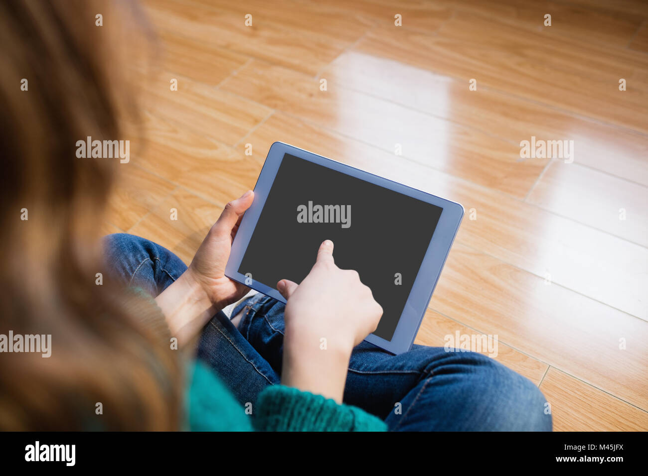 Woman sitting on the floor while using her tablet Stock Photo - Alamy