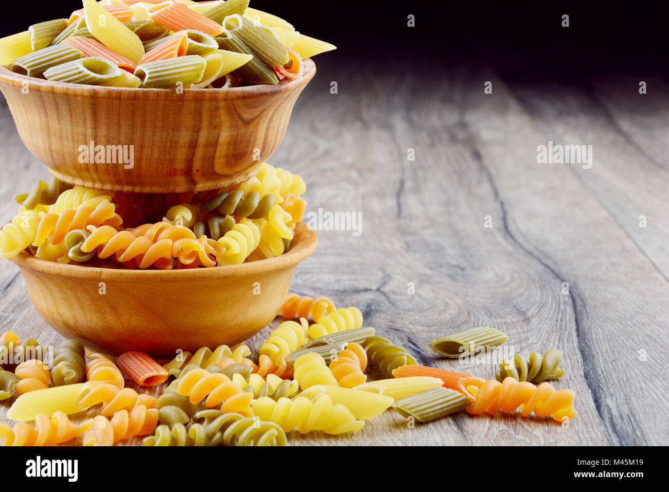 Raw eliche and penne tricolori pasta in the wooden bowls Stock Photo ...