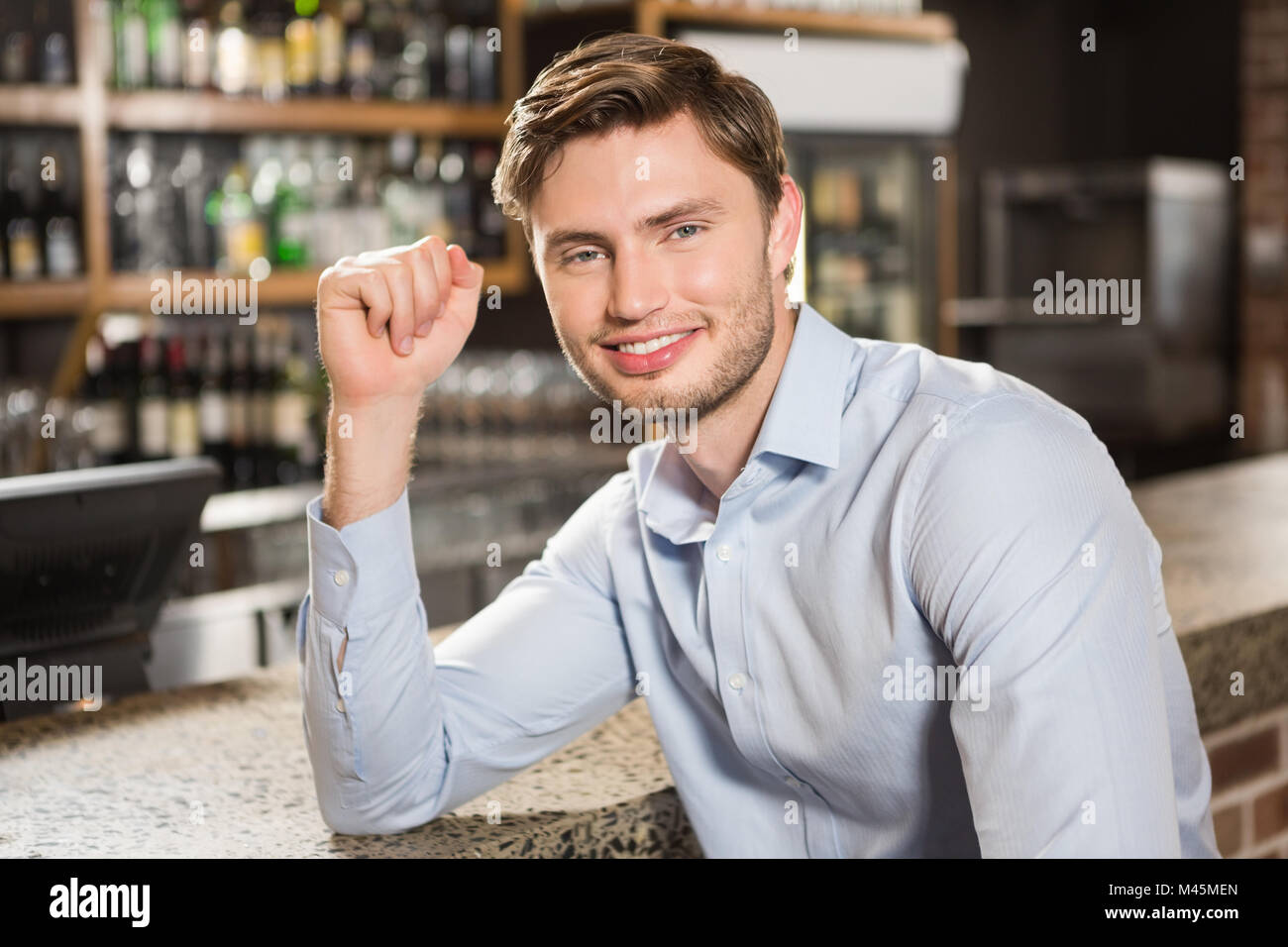 Handsome man leaning his elbow on the counter Stock Photo - Alamy