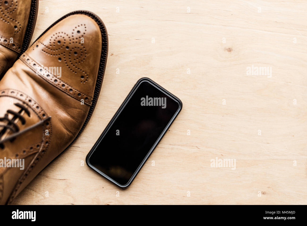 top view of smartphone and brown leather shoes on wooden surface Stock ...