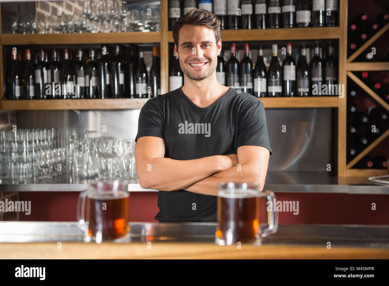 Handsome bar tender standing behind his counter Stock Photo - Alamy