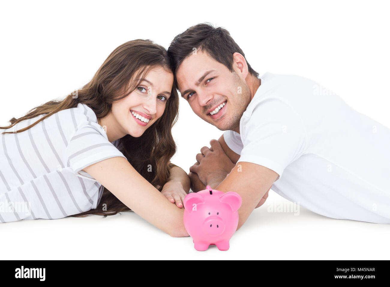 Happy couple lying on the floor with piggy bank Stock Photo - Alamy