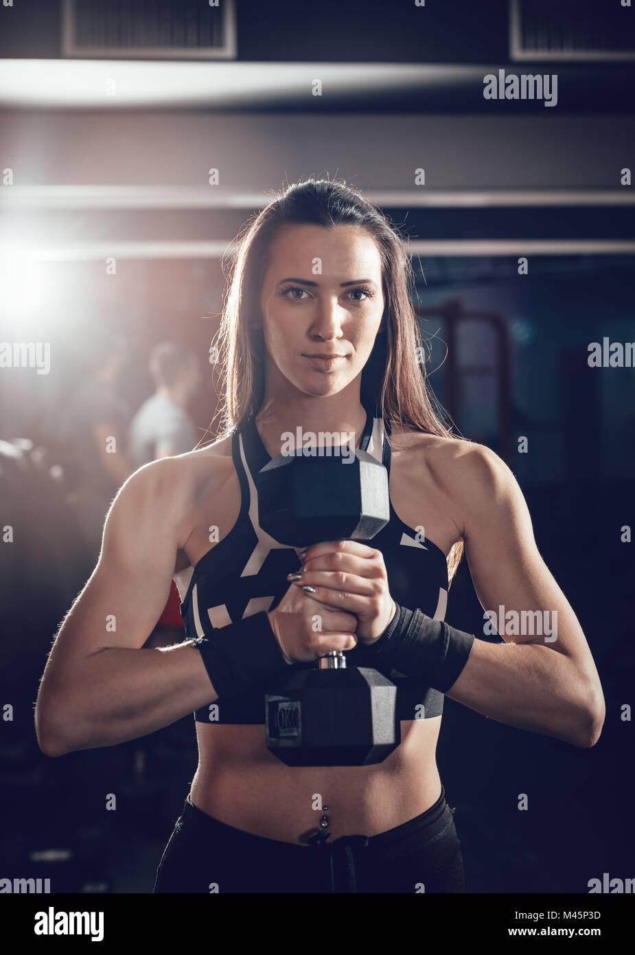 Young muscular beautiful woman doing hard exercise with dumbbell on ...