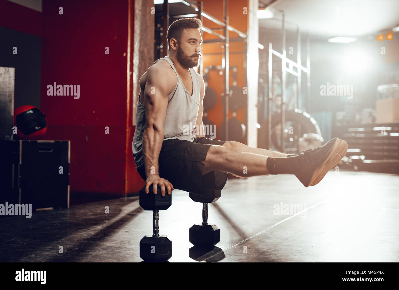 Young muscular man doing hard exercise at the gym. His whole weight is ...