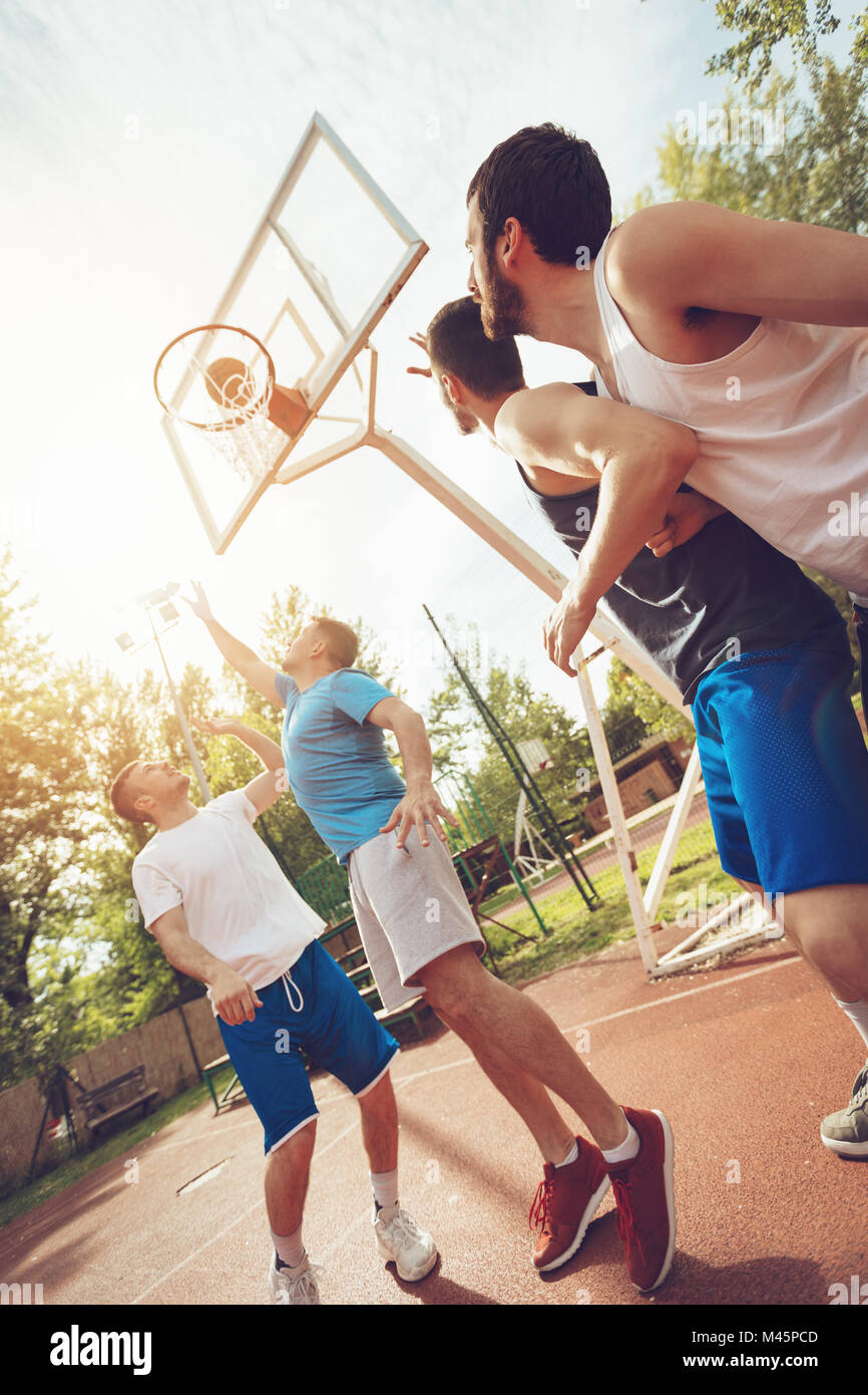 Four basketball players have a training outdoor. They are playing and ...