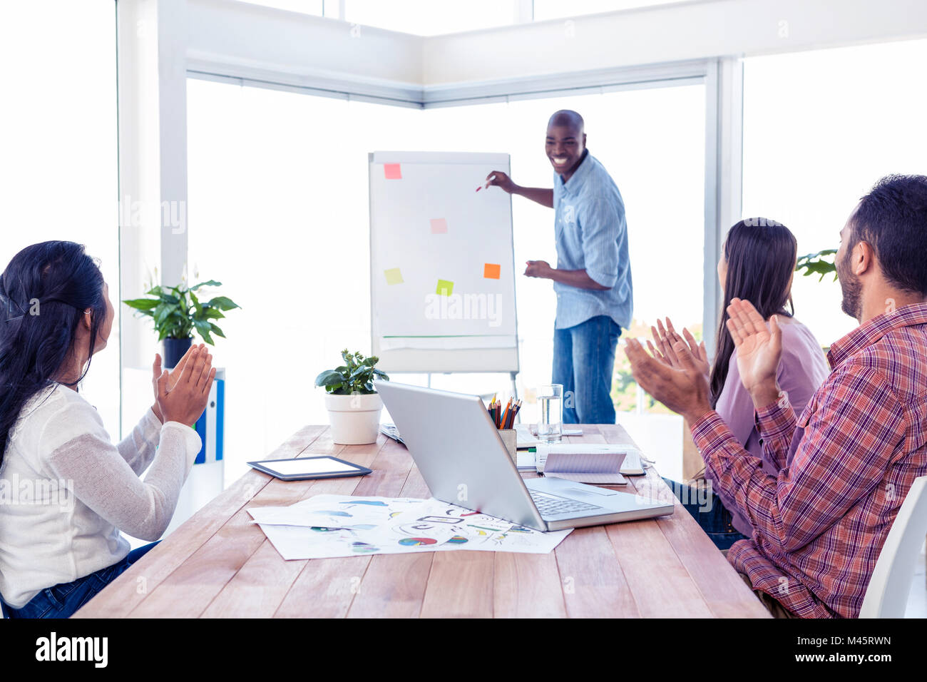 Cheerful businessman giving presentation while team applauding in ...