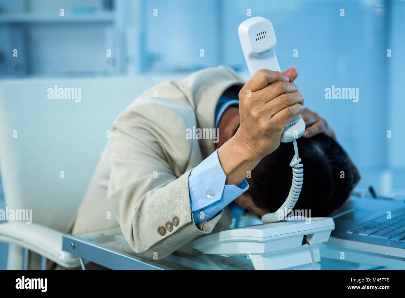 Overwhelmed asian businessman answering the phone Stock Photo - Alamy