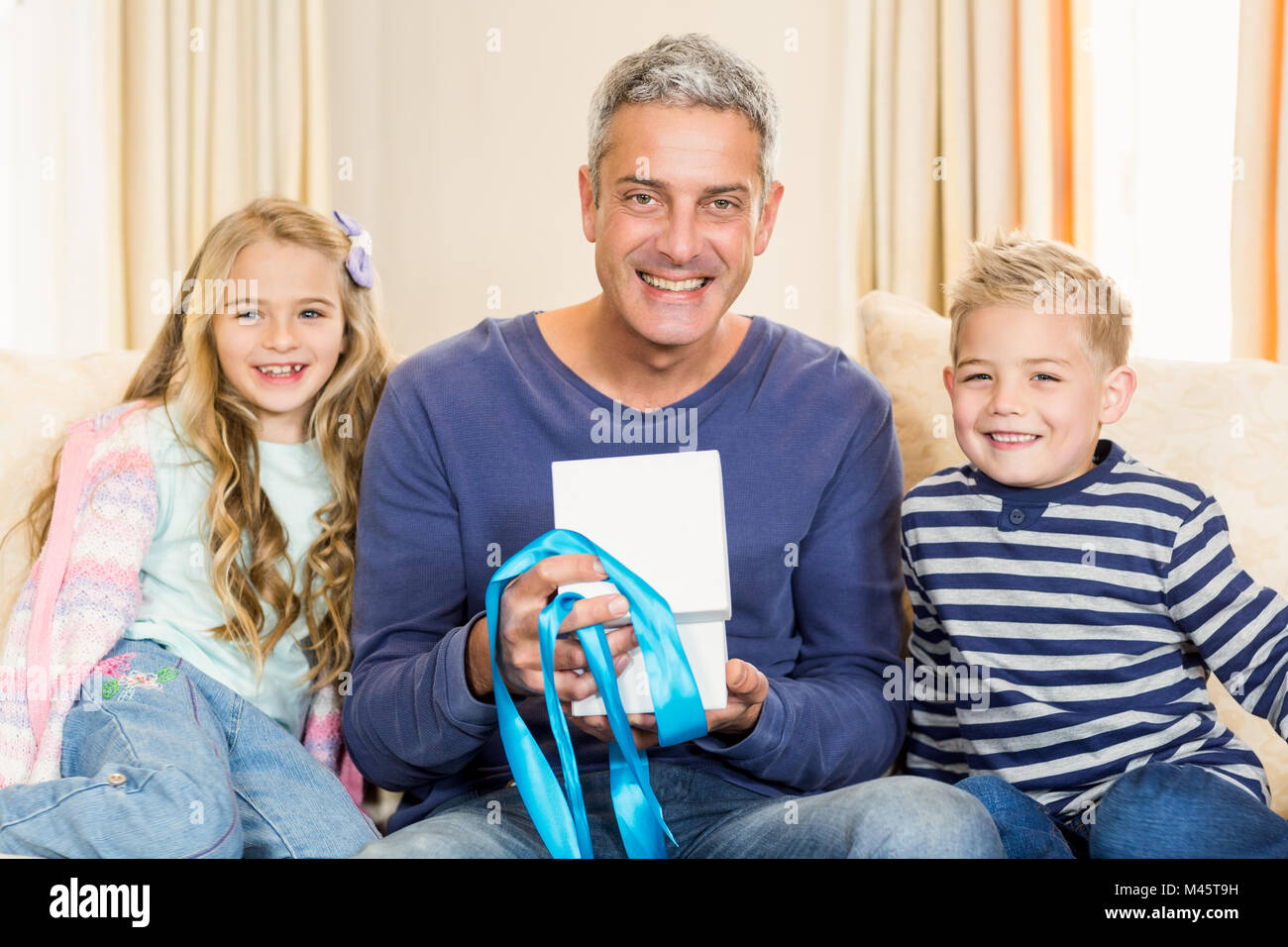 Father opening gift given by children on sofa Stock Photo - Alamy
