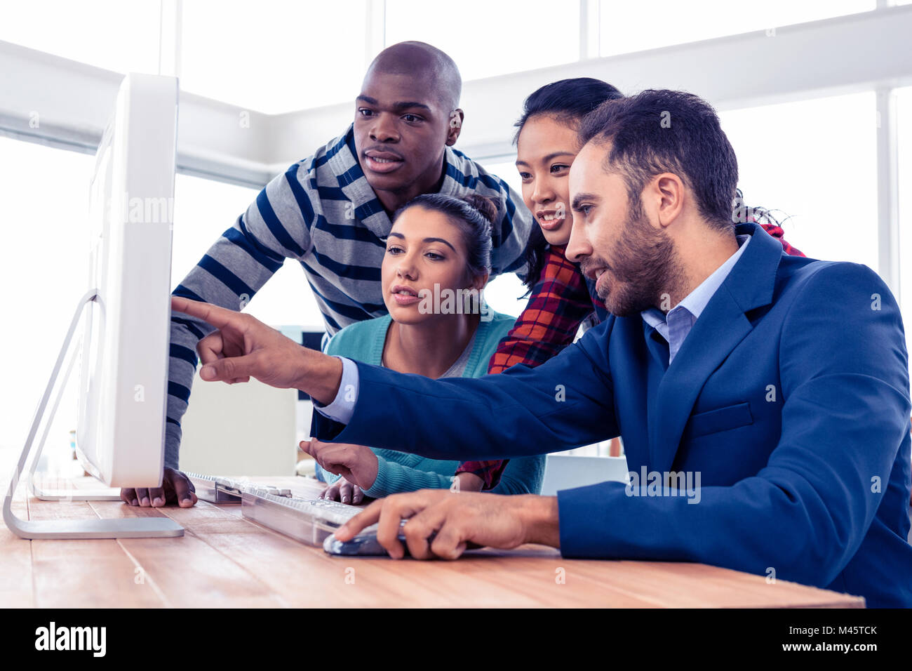 Businessman explaining colleagues over computer Stock Photo - Alamy