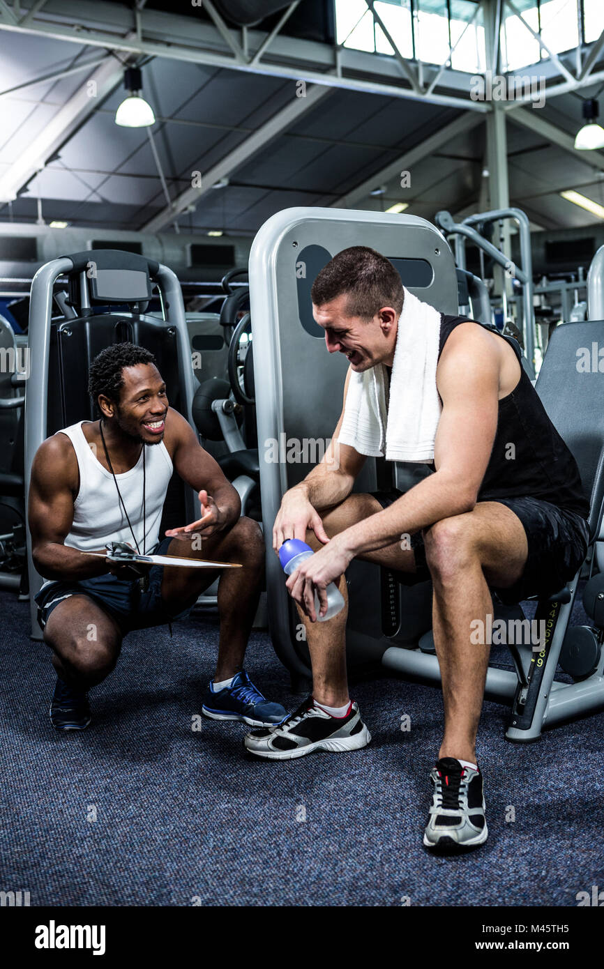 Muscular man discussing performance with trainer Stock Photo - Alamy