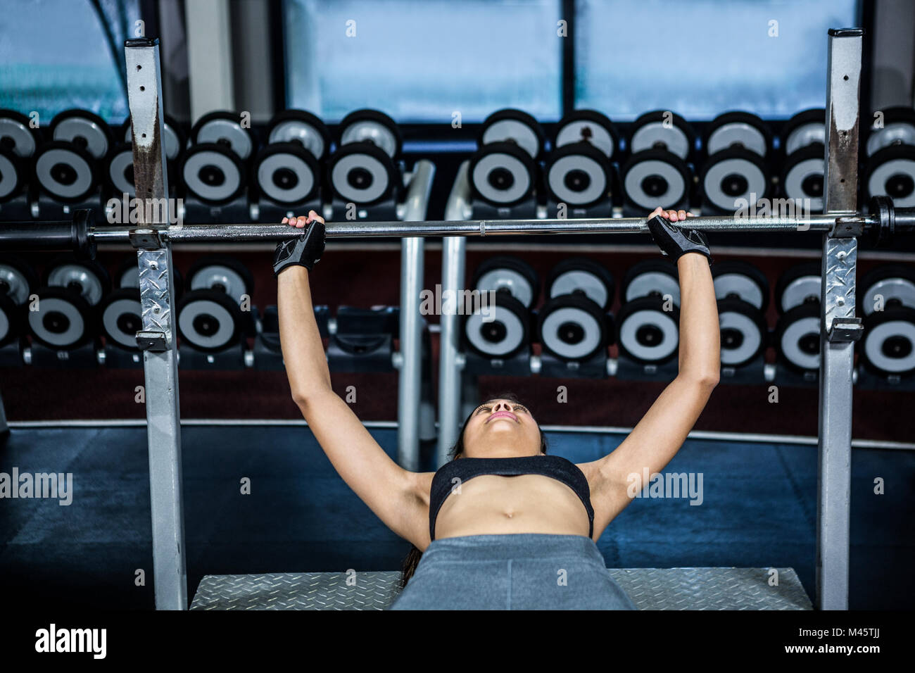 Fit woman lifting barbell while lying on bench Stock Photo - Alamy