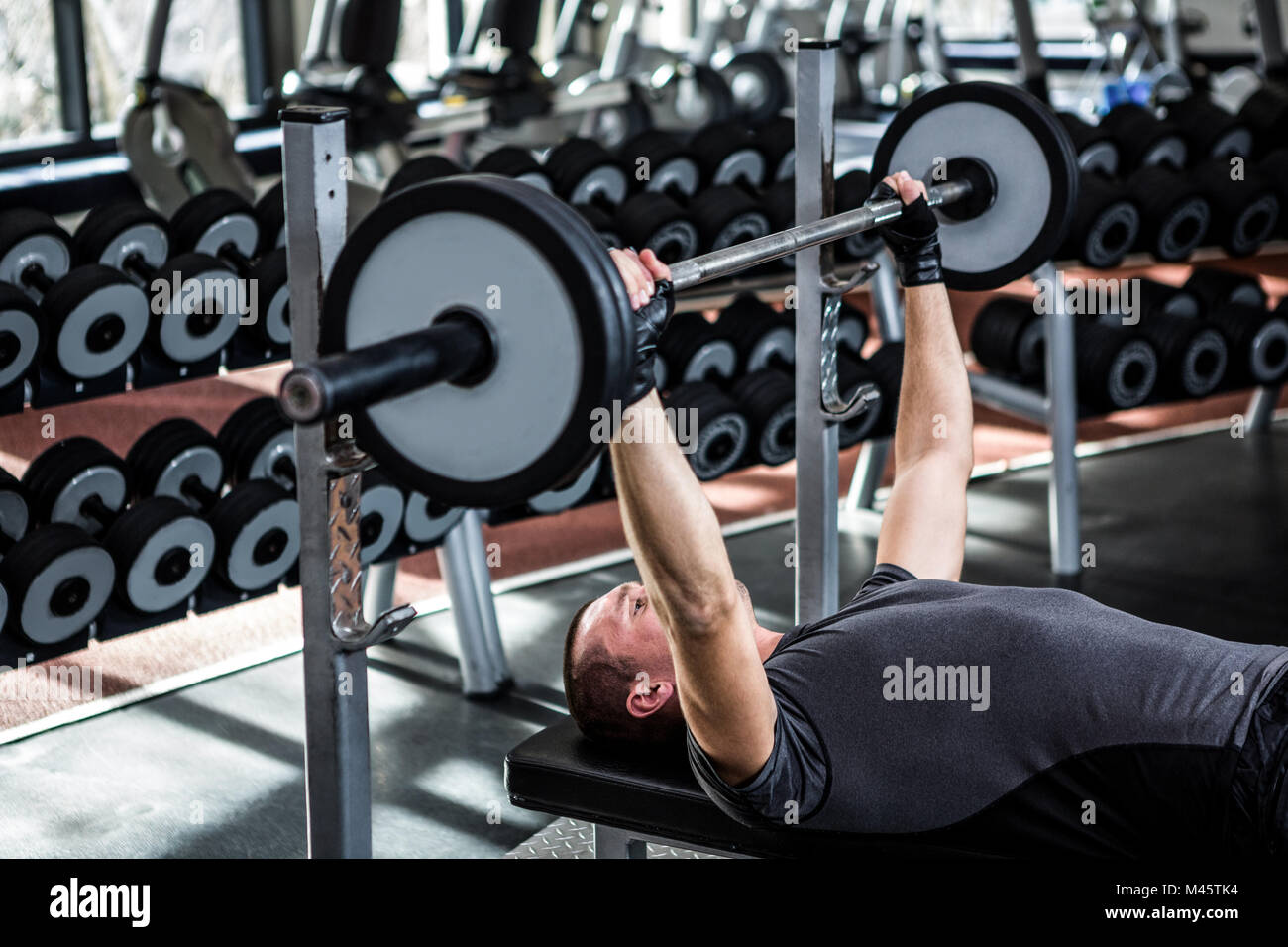Muscular man lifting barebell while lying on bench Stock Photo - Alamy