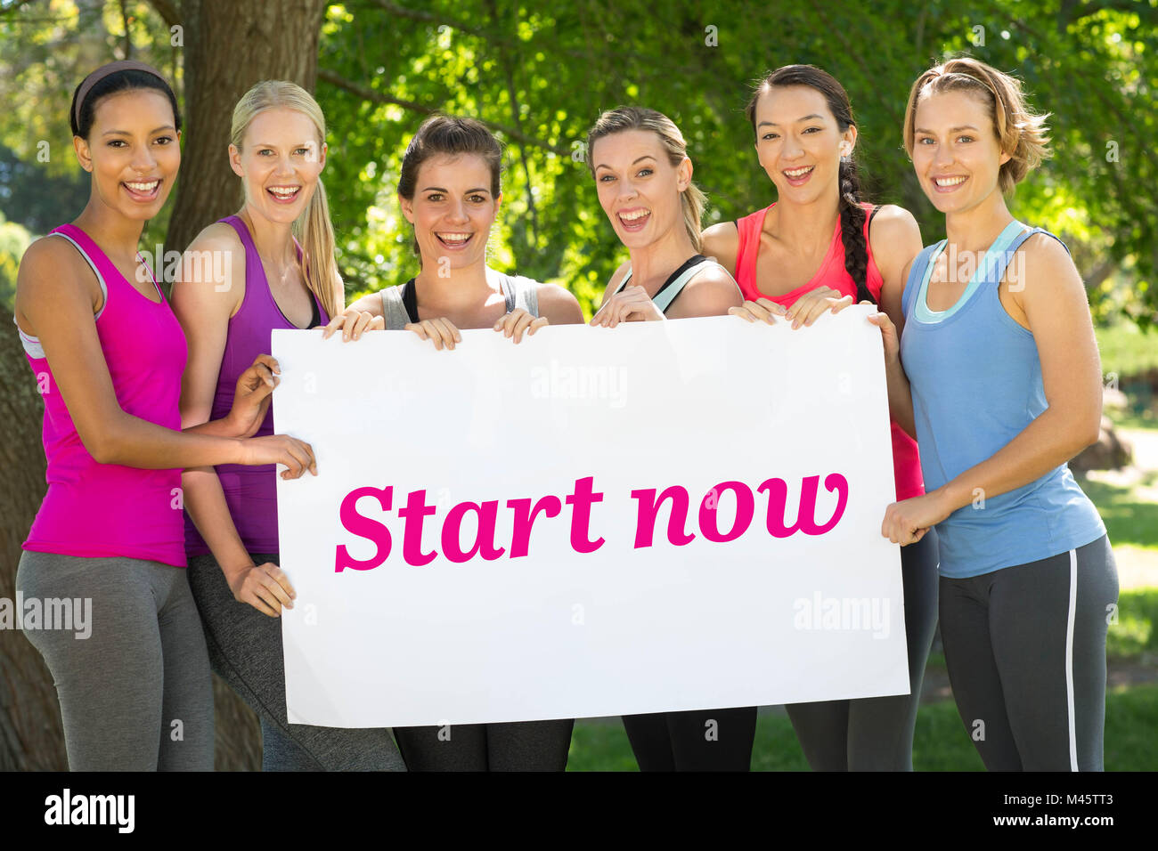 Start now against fitness group holding poster in park Stock Photo - Alamy
