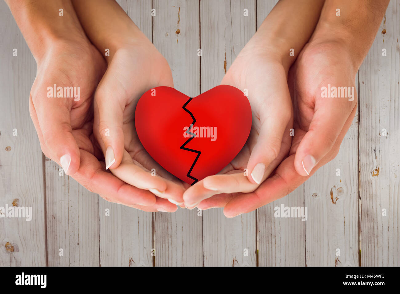 Composite image of couple holding broken heart in hands Stock Photo - Alamy