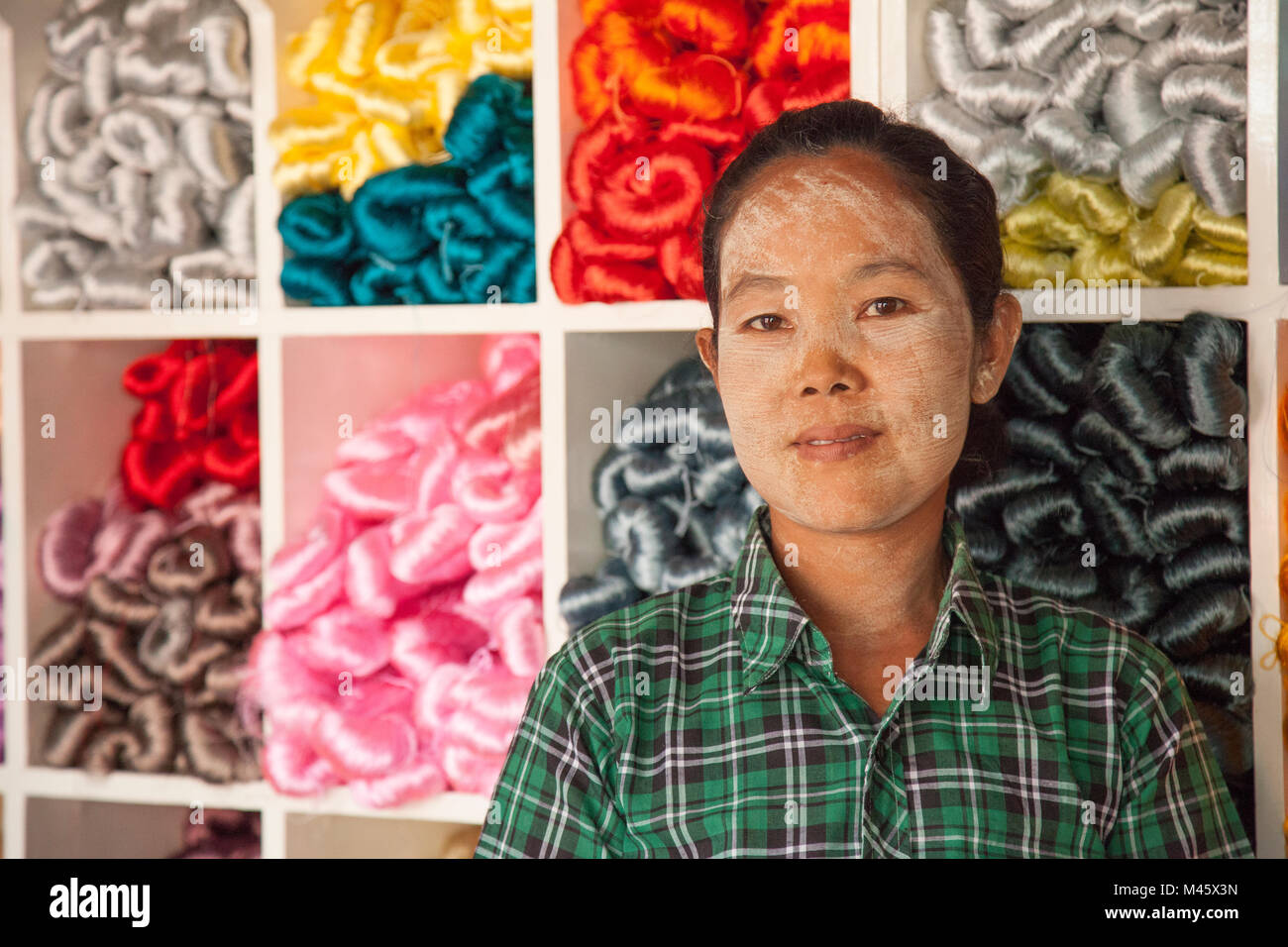 working woman with Thanaka paste on face and Threads in fabric factory ...