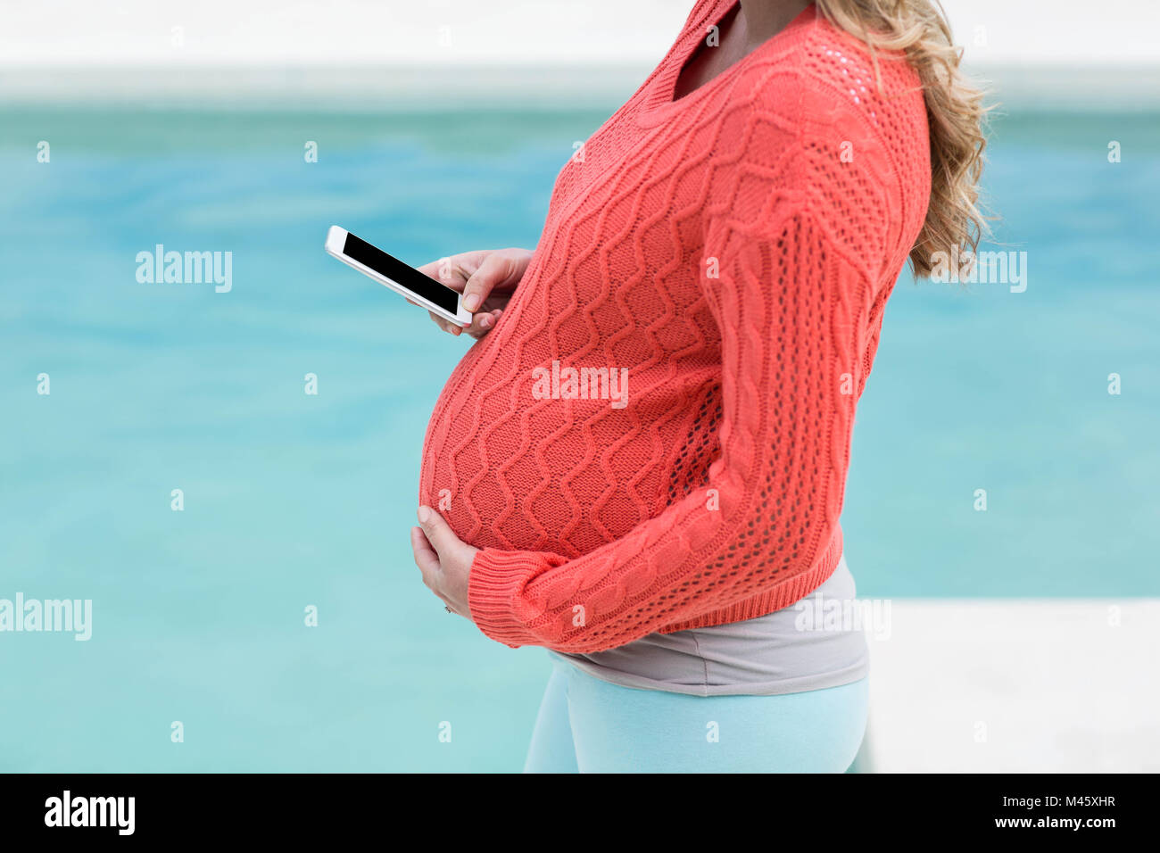 Pregnant woman touching her belly and texting Stock Photo - Alamy