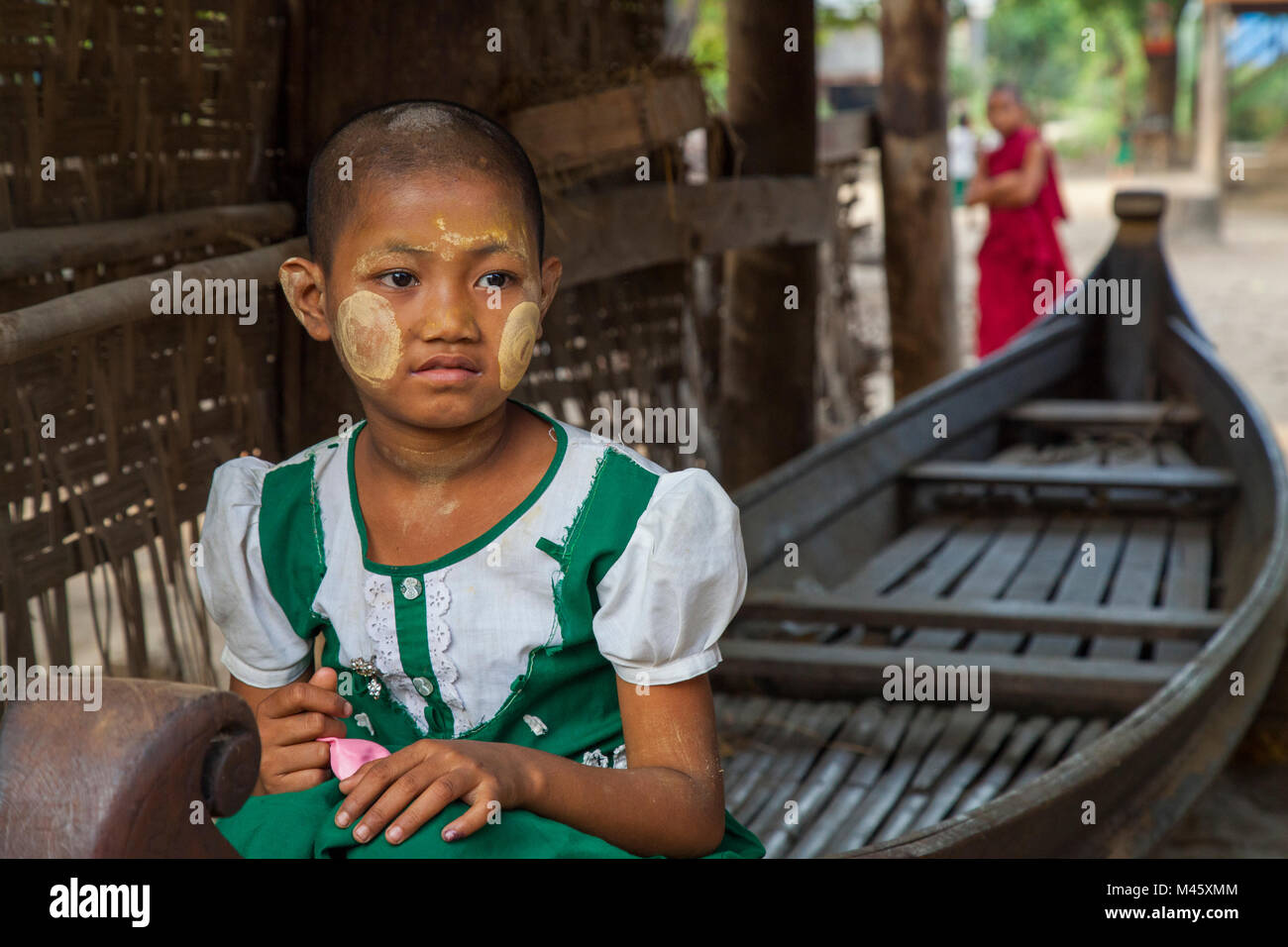 Young burmese school girl with traditional Thanaka Paste on her face in a canoe boat in Bagan ...