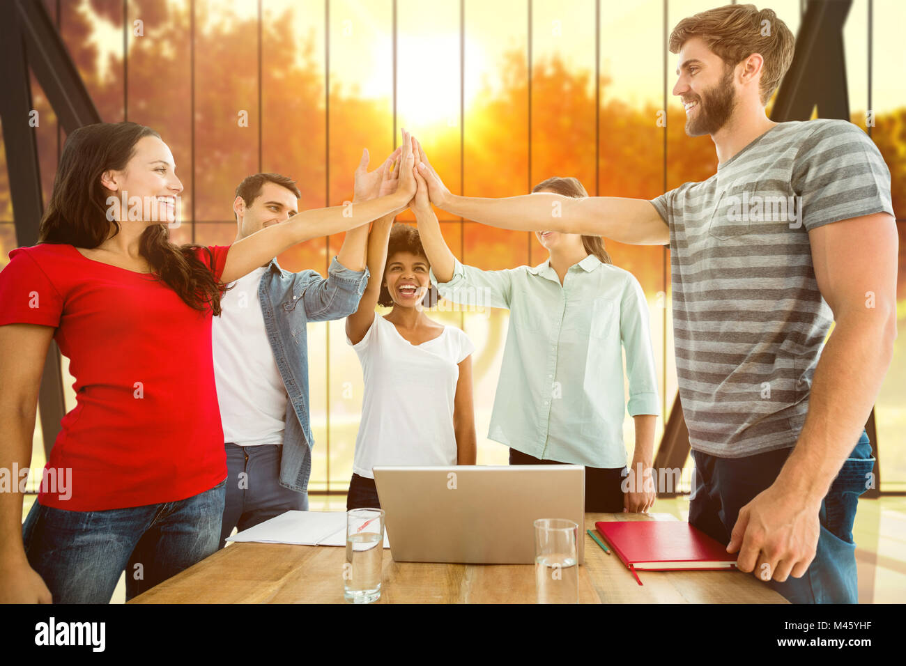 Composite image of happy business team putting their hands together ...
