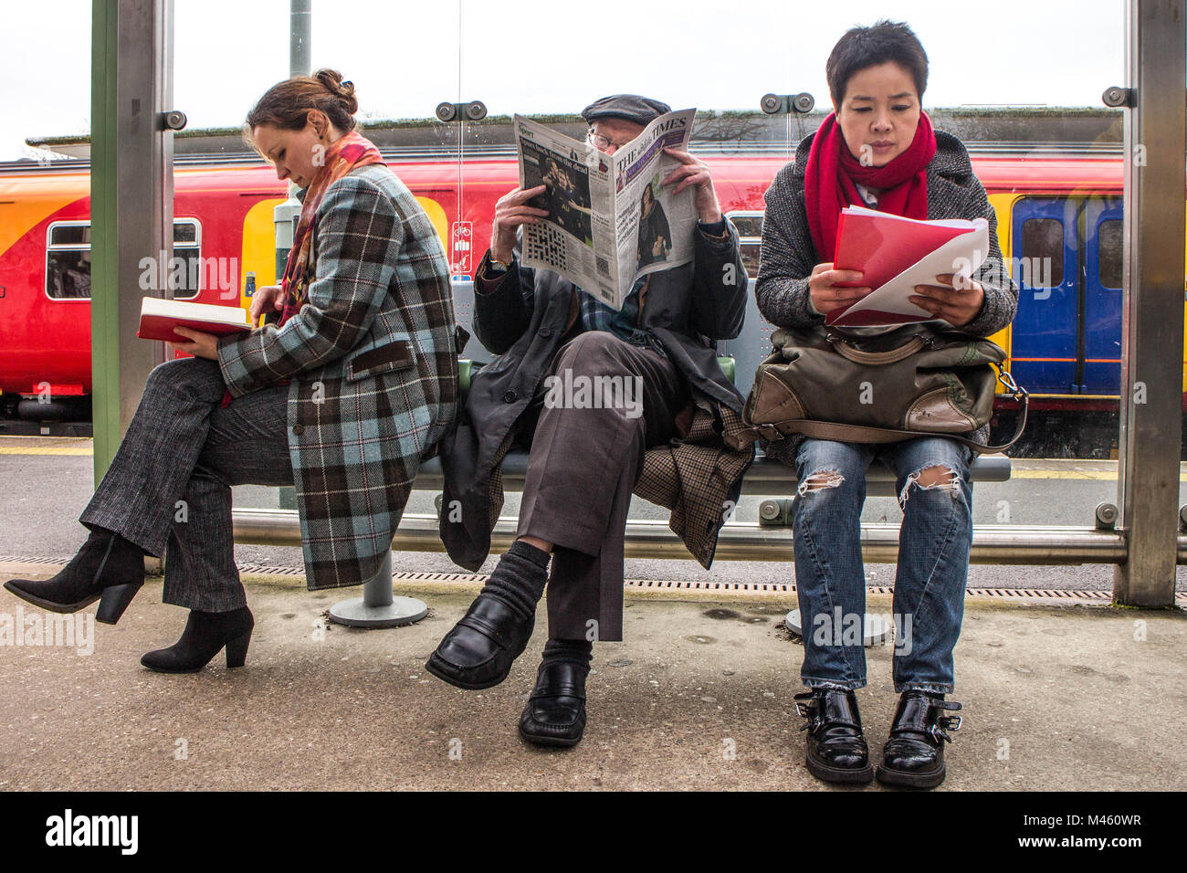 Three Strangers Sitting On A Railway Station Bench Reading A Book ...