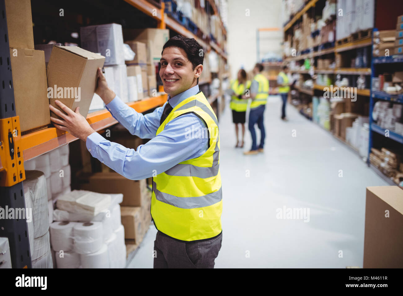 Smiling warehouse worker taking package in the shelf Stock Photo - Alamy