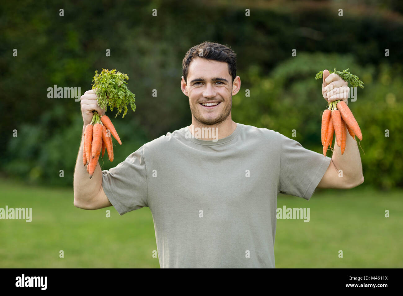 Portrait of young man holding bunch of carrots Stock Photo - Alamy