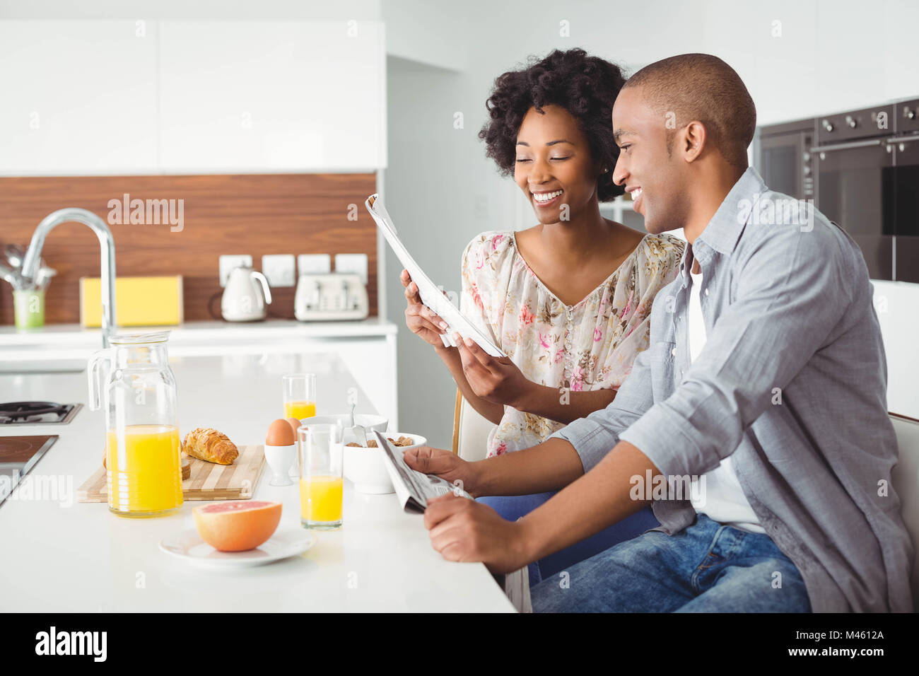 Smiling couple reading and eating breakfast together Stock Photo - Alamy