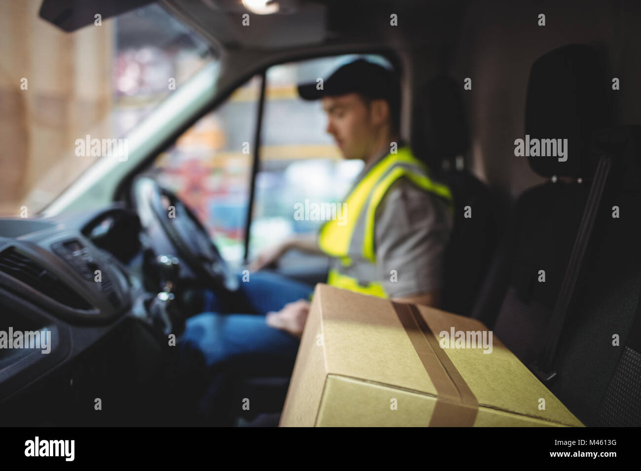 Delivery driver driving van with parcels on seat Stock Photo - Alamy