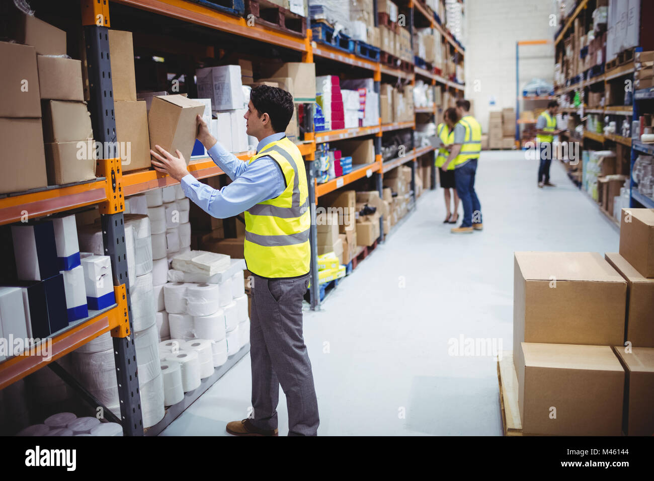 Smiling warehouse worker taking package in the shelf Stock Photo - Alamy