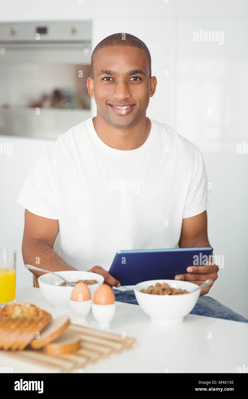 Young man using tablet and eating breakfast in kitchen Stock Photo - Alamy