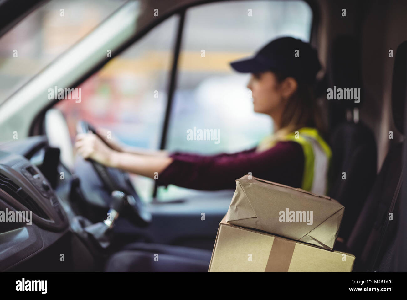 Delivery driver driving van with parcels on seat Stock Photo - Alamy
