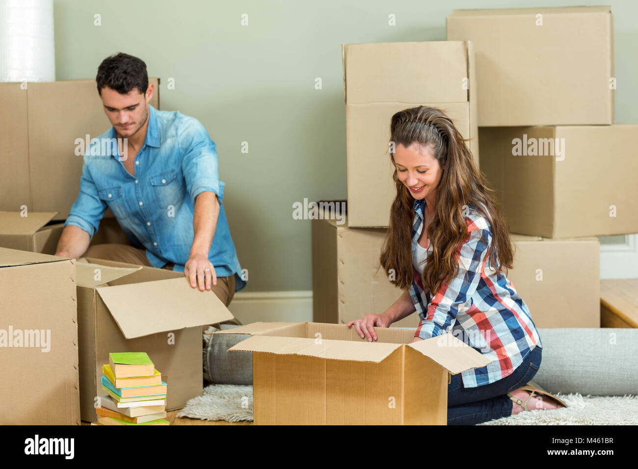 Young couple unpacking carton boxes in their new house Stock Photo - Alamy