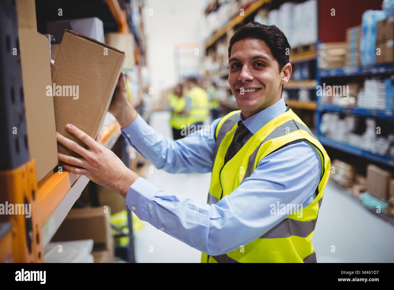 Smiling warehouse worker taking package in the shelf Stock Photo - Alamy