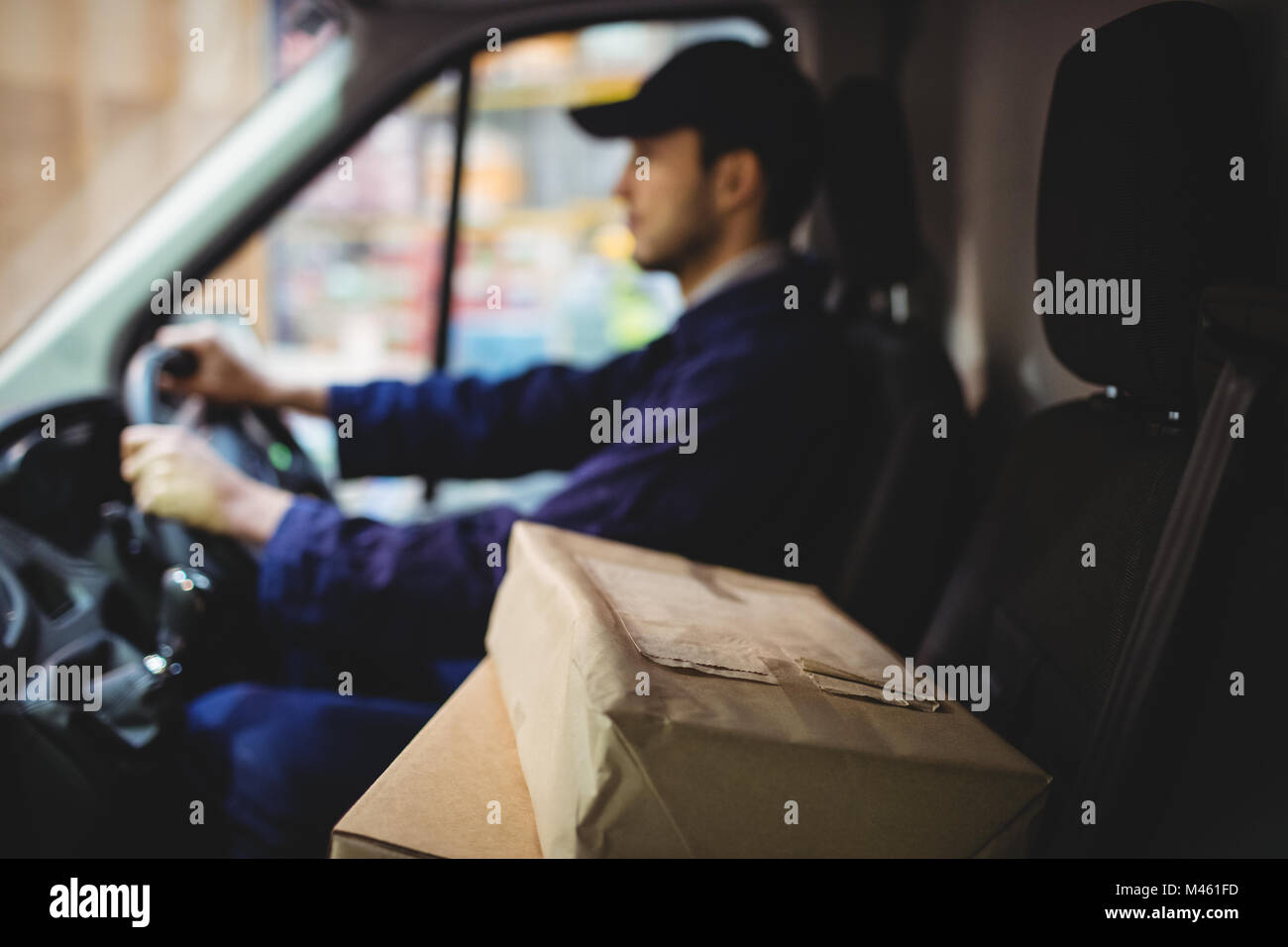 Delivery driver driving van with parcels on seat Stock Photo - Alamy