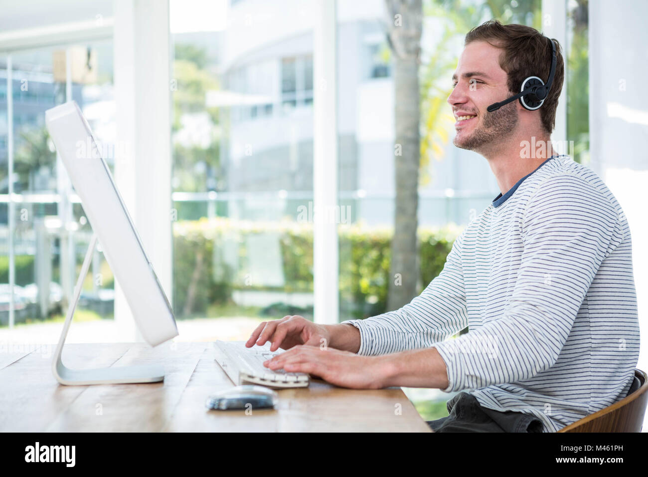 Handsome man working on computer with headset Stock Photo - Alamy