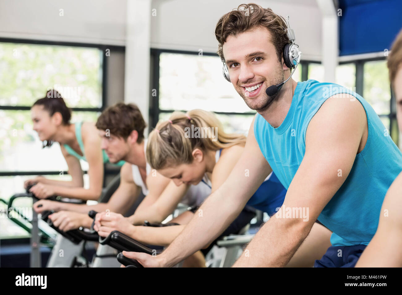 Fit group of people using exercise bike together Stock Photo - Alamy