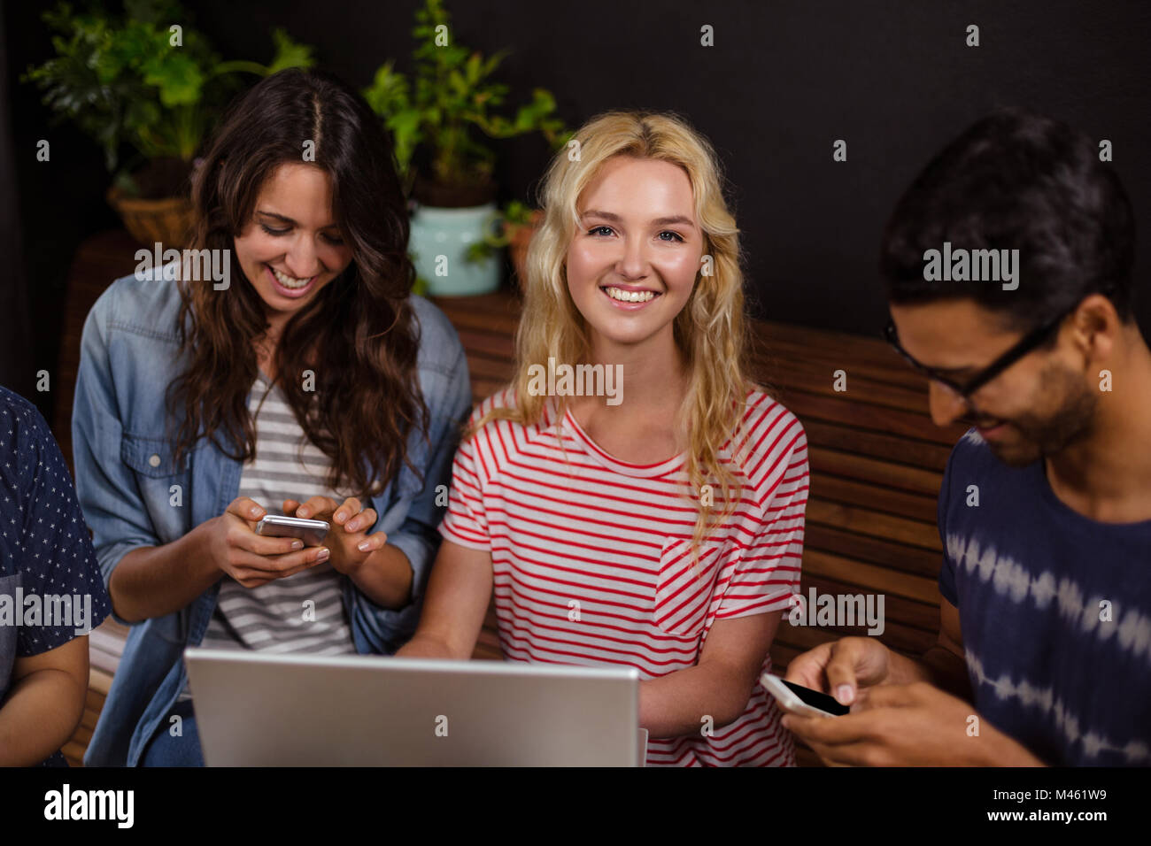 Smiling friends enjoying coffee together and using technologies Stock ...