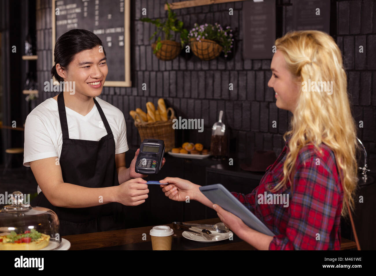 Smiling barista taking credit card from customer Stock Photo - Alamy