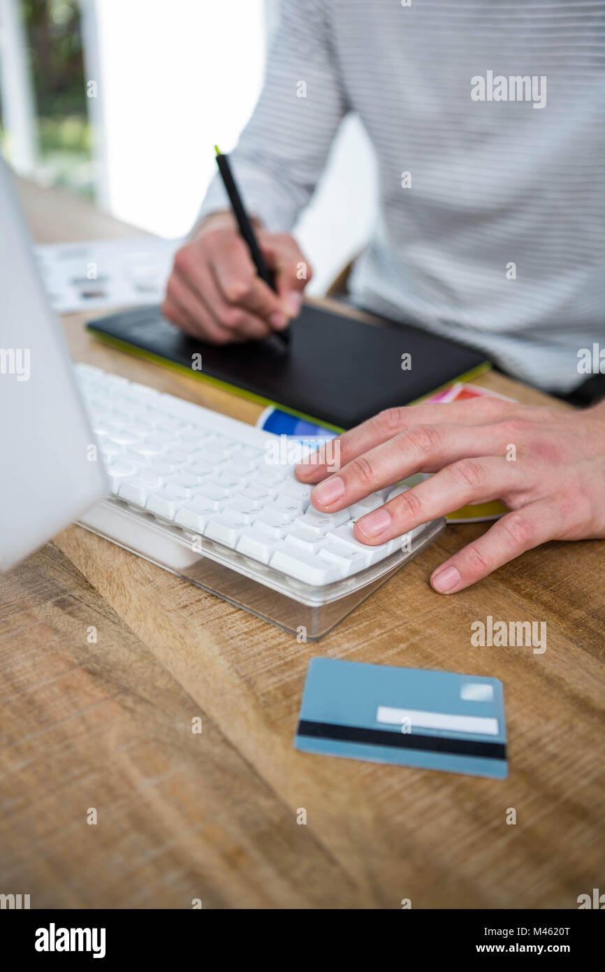 Masculine hands taking notes and typing on keyboard Stock Photo - Alamy