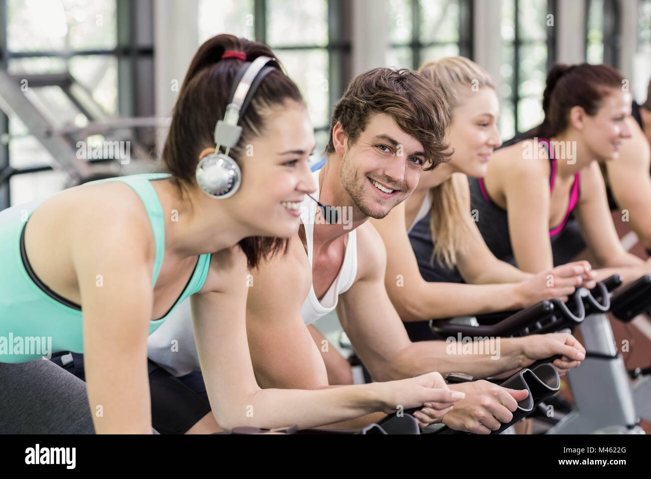 Fit group of people using exercise bike together Stock Photo - Alamy