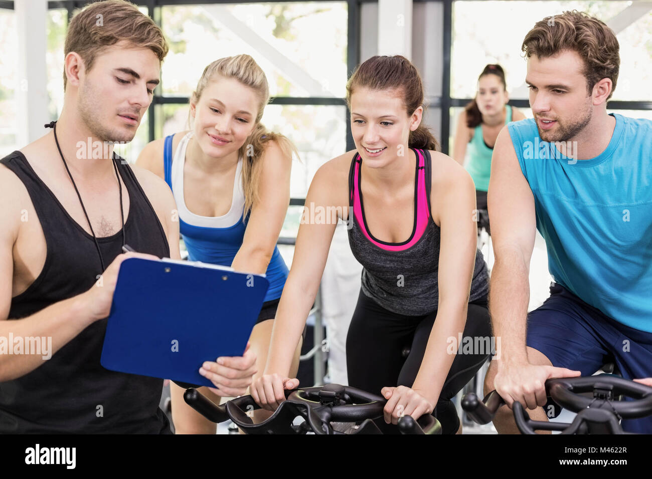 Fit group of people using exercise bike together Stock Photo - Alamy