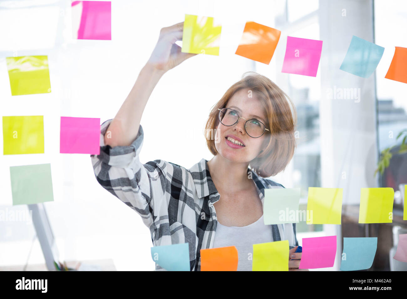 smiling hipster woman sticking notes on a notice board Stock Photo - Alamy