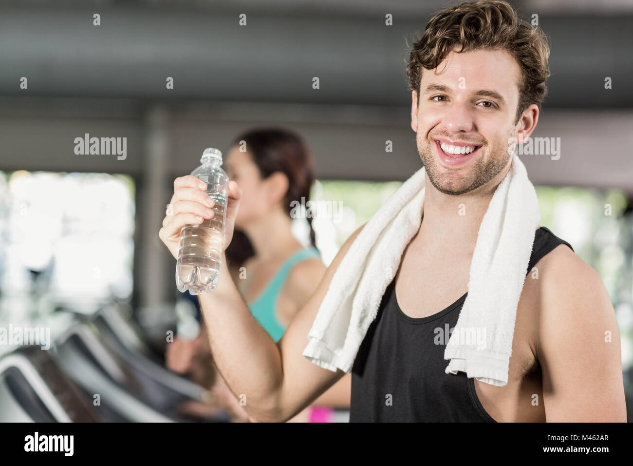 Athletic man drinking water while running on treadmill Stock Photo - Alamy