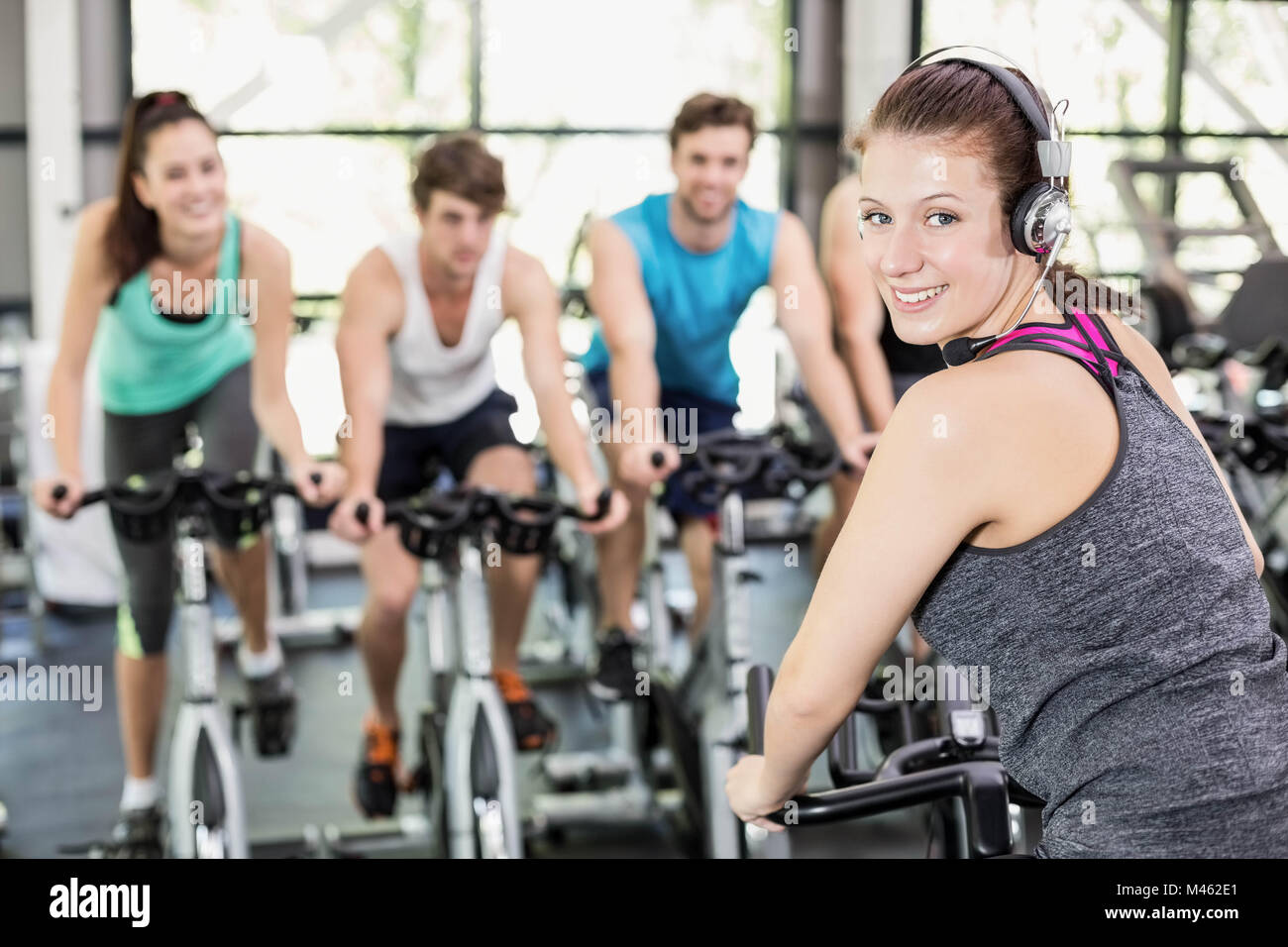 Fit group of people using exercise bike together Stock Photo - Alamy