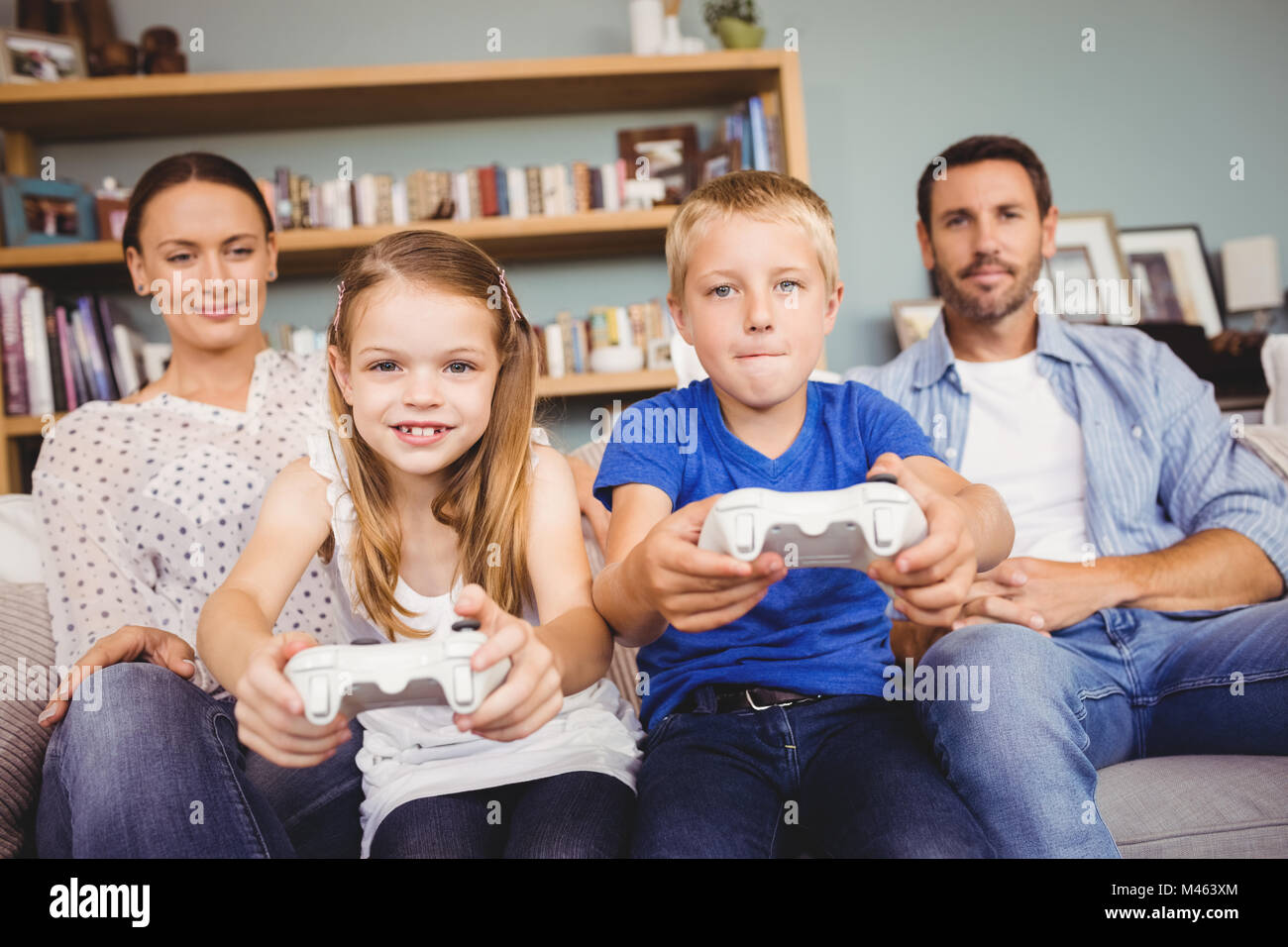 Smiling siblings playing video games with parents Stock Photo - Alamy