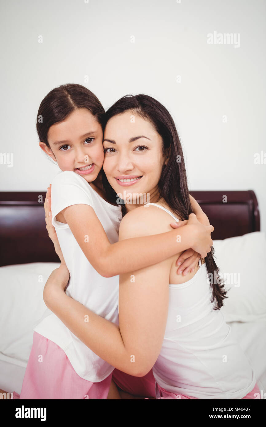 Portrait of happy mother hugging daughter on bed Stock Photo - Alamy